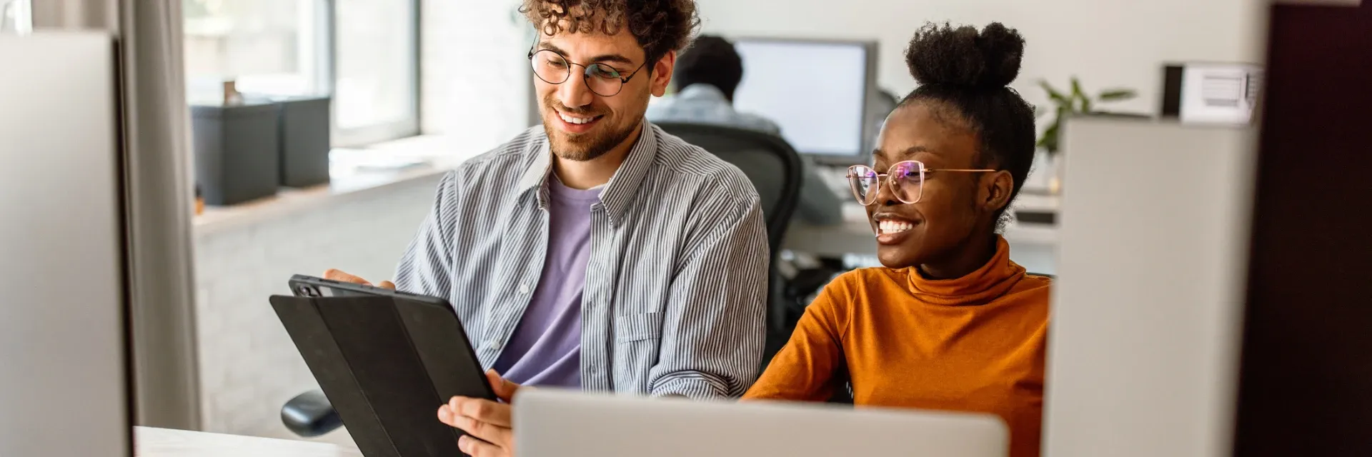 Dois colegas universitários sorridentes analisando tablet em uma sala ...